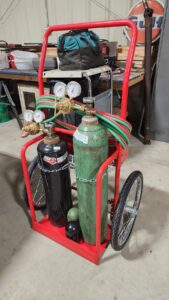 red steel welding cart hauls welding tanks torch equipment over rough terrain