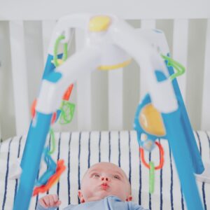 Nurture Smart - Baby Play Gym - Interactive Infant Play Gym, Safely Fit in Crib - With Cause and Effect Hanging Toys that Stimulate Brain & Muscle Development - Developmental Toy