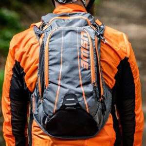 USWE Airborne - Hydration Pack with Hydration Bladder, Bounce Free Backpack for MTB, Cycling, Mountain Biking (15L, Gray/Orange)