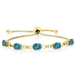 gem stone king 18k yellow gold plated silver london blue topaz and white lab grown diamond tennis bracelet for women (5.02 cttw, gemstone birthstone, oval 7x5mm, fully adjustable up to 9 inch)