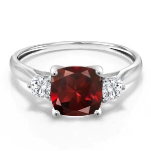 gem stone king 10k white gold red garnet and white moissanite 3 stone engagement ring for women (2.11 cttw, cushion 7mm, gemstone january birthstone) (size 5)