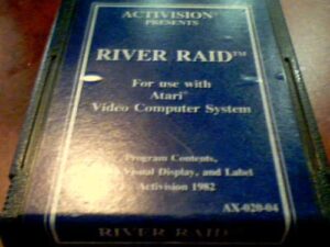 1982 activision presents "river raid" video game cartridge for atari 2600---blue image label version #ax-020-04 (activision presents river raid for use with atari video game system---program contents audio visual display, and label---activision 1982 ax-02