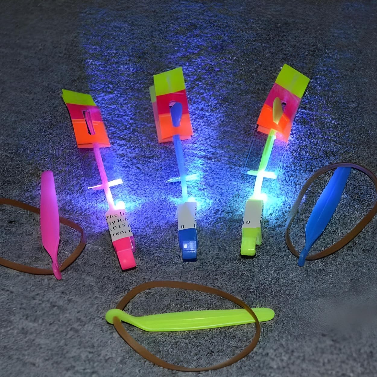 Dozen Light Up LED Slingshot Style Flying Helicopter Toy